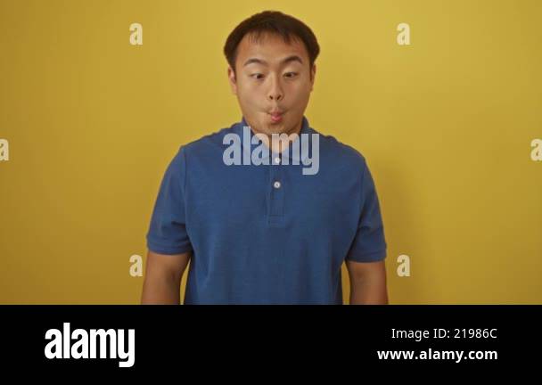Young chinese man standing making fish face with crazy, squinting eyes ...