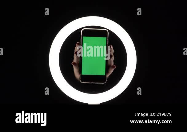 female hands show the phone close-up on a black background. green ...