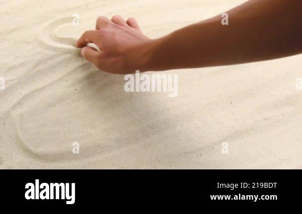 hand draws the inscription "Sand Sea" on the sand. Sunny coast of the ...