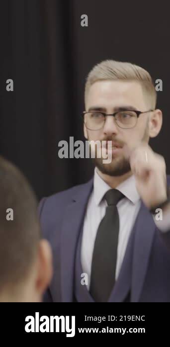 Vertical shot of auctioneer in formal suit standing at podium and ...