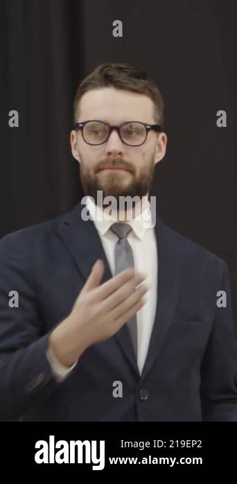 Vertical shot of auctioneer in suit standing on stage and calling out ...