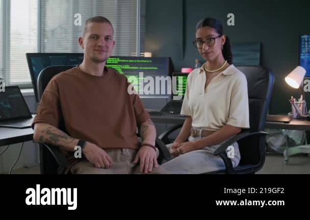 Medium shot portrait of young male Caucasian programmer and his female biracial colleague in ...