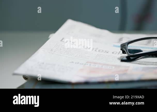 A close up of the glasses on the newspaper. A moving sideways shot ...