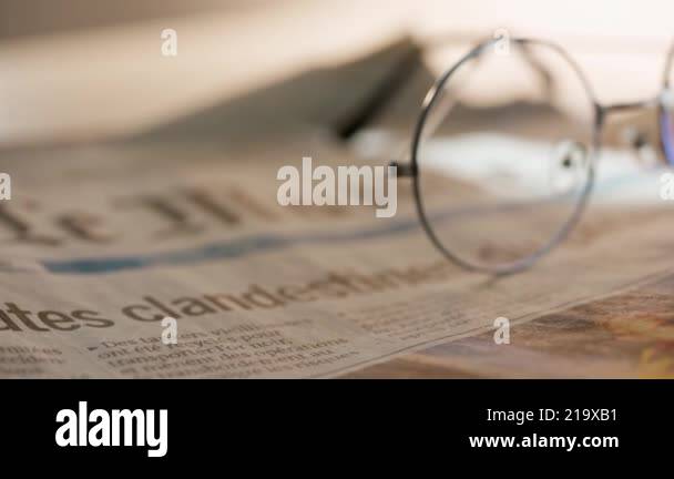 A close up of the glasses on the newspaper. A moving sideways shot ...