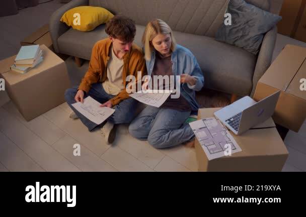 A young man and woman are in the living room discussing a housewarming ...