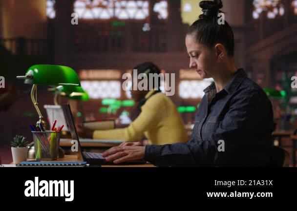 Portrait of a confident librarian working on her laptop in a public ...