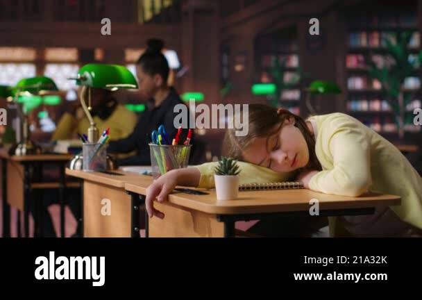 Teacher waking up her student sleeping on the study desk at the library ...