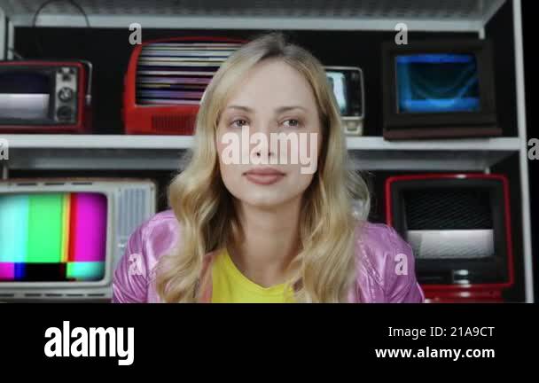 Female looking around with a wall of television screens behind her with ...