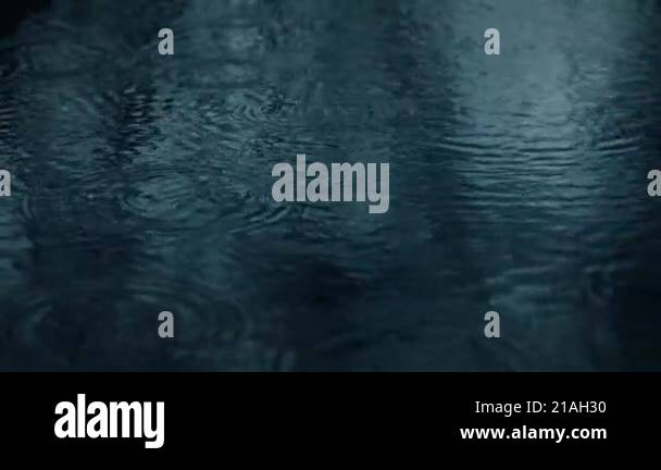 A serene and tranquil scene where gentle rain softly falls, creating ripples on a dark ...
