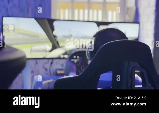 Man in gaming chair experiencing race simulation using multi-screen ...