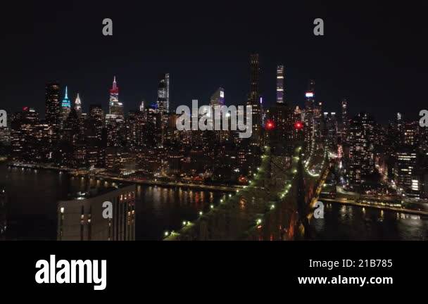 Aerial views capture the illuminated Queensboro Bridge alongside the ...