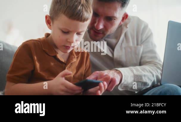 A dad carefully monitors his young sons smartphone browsing activity ...