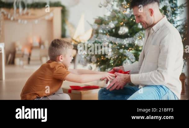 A touching moment as a young son hands a Christmas present to his ...