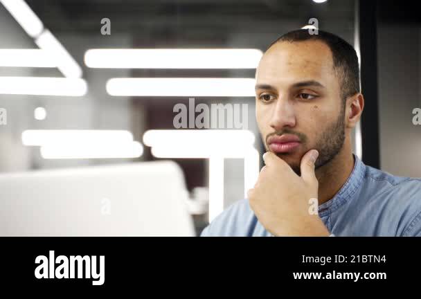 Thoughtful African American businessman working on laptop in office ...
