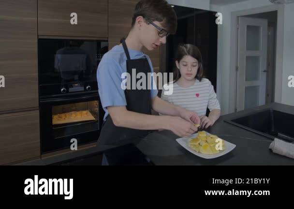 Happy teenage brother wearing apron and sister are tasting freshly ...