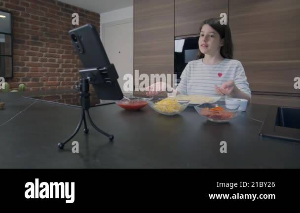 Young girl making pizza and recording cooking podcast, showcasing her ...
