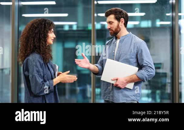 Two colleagues, one male and one female, make eye contact, smile, shake ...