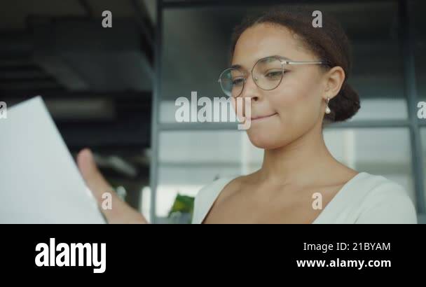 Close-up shot of a stylish, focused young woman with glasses reviewing ...
