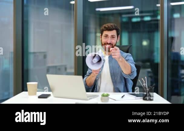 Young businessman with a megaphone makes an announcement and points his ...