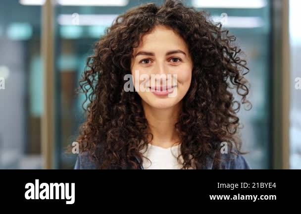 Beautiful businesswoman with curly hair smiling in modern office ...