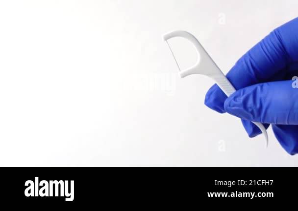Dental floss with plastic handle on white background. Dentist's hand in ...