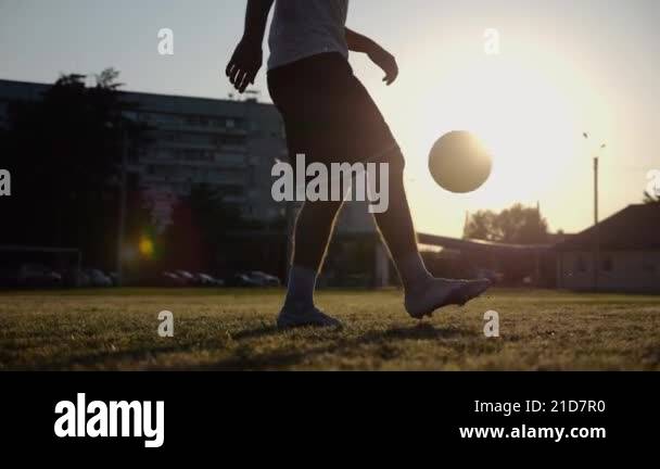 Legs of young man kicking ball at green field. Male feet of ...