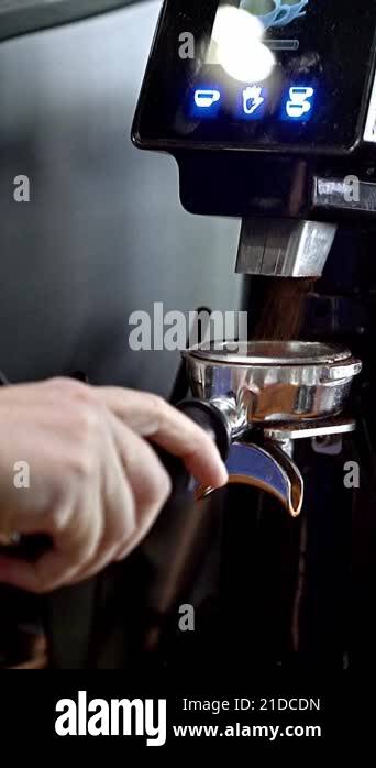 Barista grinding coffee beans on professional equipment, focusing on ...