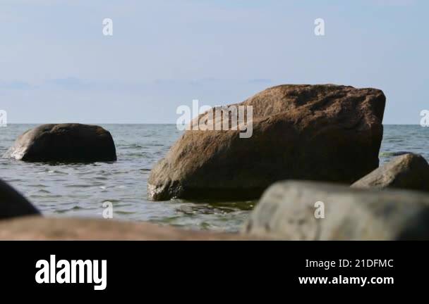 Serene coastal scene with large rocks scattered along shore, beneath ...