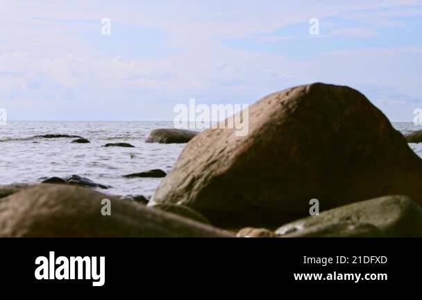 Serene coastal scene with large rocks scattered along shore, beneath ...