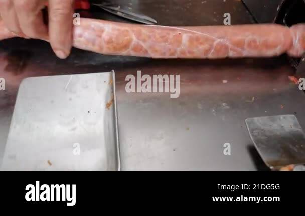 sausages fastening with white tiny lines on the metal plate. Worker makes sausage products on ...