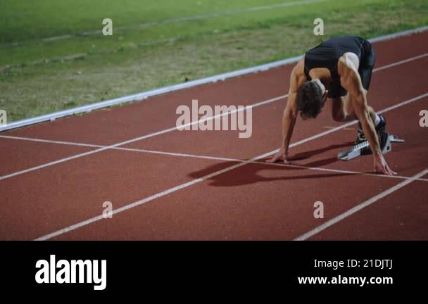 Strong Young Man Starting a Race From Track Starting Blocks Position on ...
