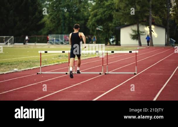 Strong Male Athlete is Running Towards an Obstacle, Hurdling, Jumping ...