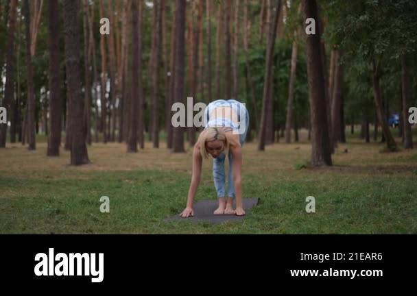 A Blonde Woman In Stylish Blue Yoga Wear Practices A Standing Split