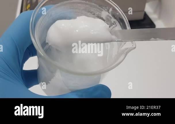 Close-up footage of a beaker containing a white emulsion being stirred ...