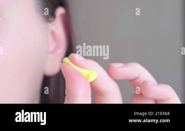 Close-up of a womans hand squeezing earplugs before inserting them into ...