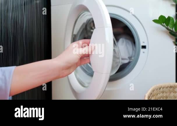 A woman opens the washing machine with clean clothes, removing damp ...