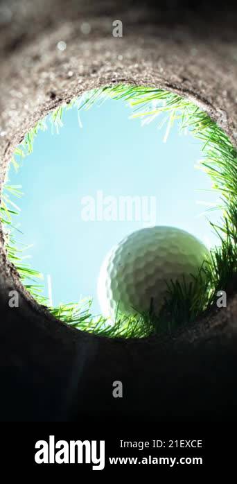 Super slow motion of falling golf ball into hole. Unique perspective ...