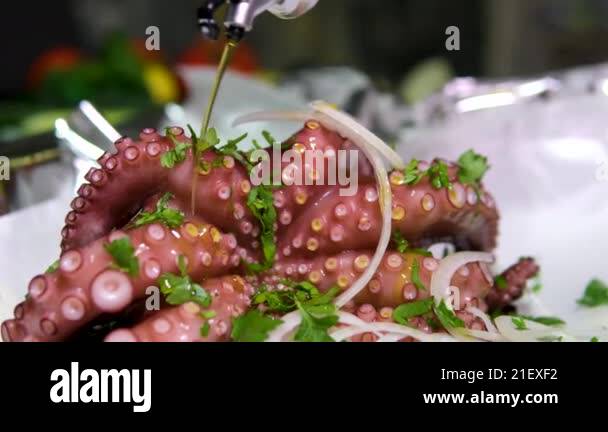 Cooked octopus garnished with olive oil, paprika and a potato plate in ...