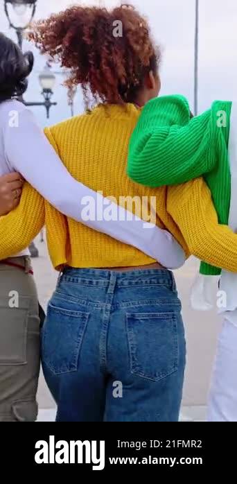 Vertical video. Rear view of young group of multiracial women walking ...