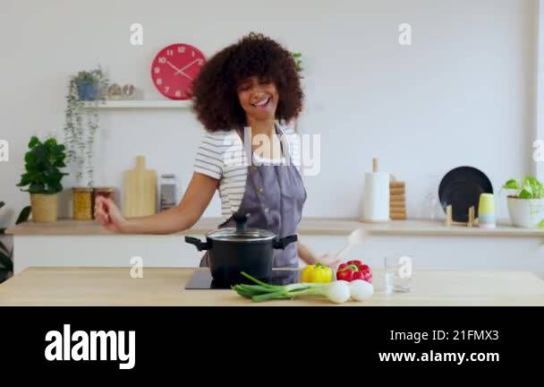 Cheerful young multiracial woman having fun singing and dancing while ...