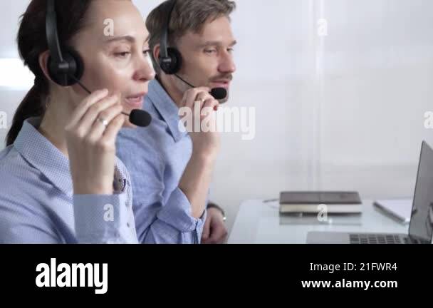Focused female call center operator in blue casual blouse is assisting clients online, providing ...
