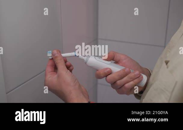 Close-up of man in shirt holding white electric toothbrush in the ...