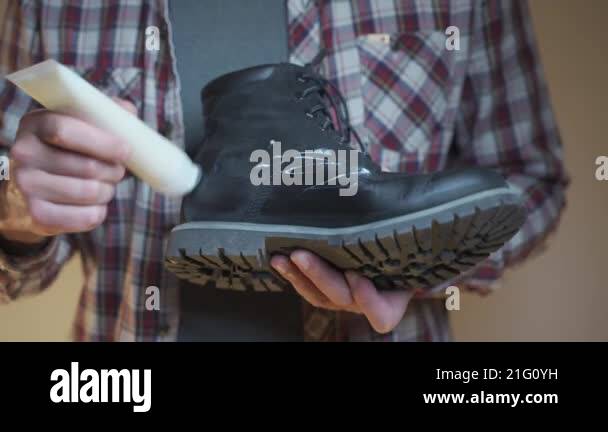 Man prepares black suede boots before fall and winter by applying a ...