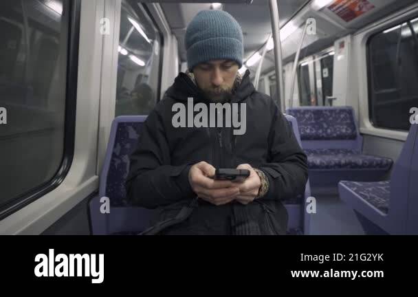 Man traveling on subway train in Hamburg sitting on blue seat and using ... Man traveling on subway train in Hamburg sitting on blue seat and using ...