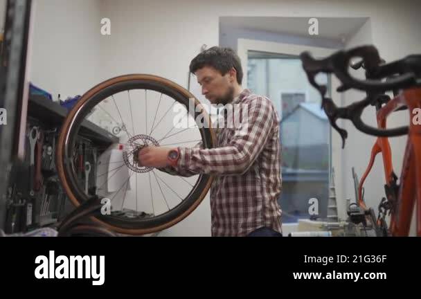 Male bicycle mechanic at work in a cycle workshop repairing wheel and ...
