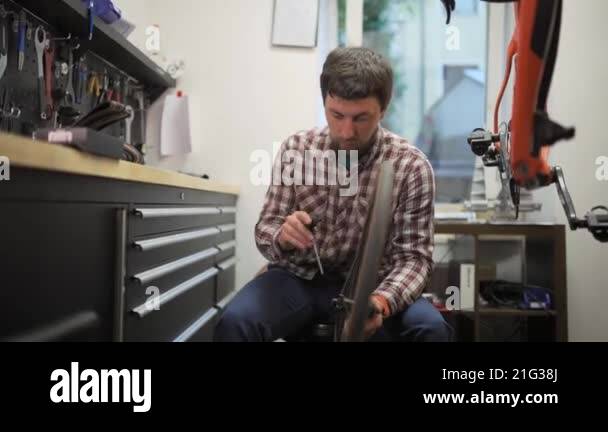 Male bicycle mechanic at work in a cycle workshop repairing wheel and ...
