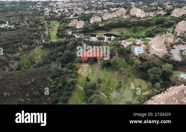 Elevated view of a serene housing complex with a small pond, tennis ...