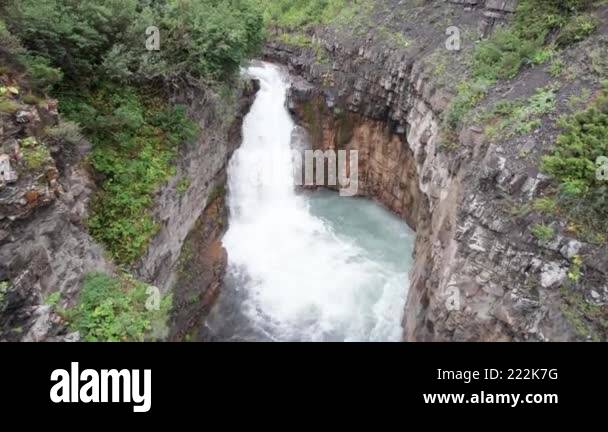 A beautiful waterfall among the rocks and a green gorge. There are ...