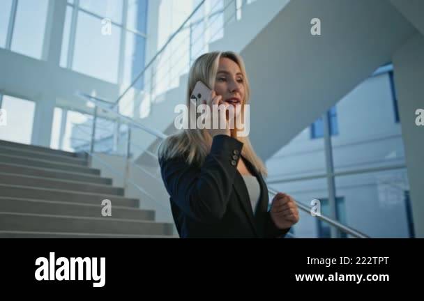 Confident businesswoman speaking mobile phone in modern office hall ...
