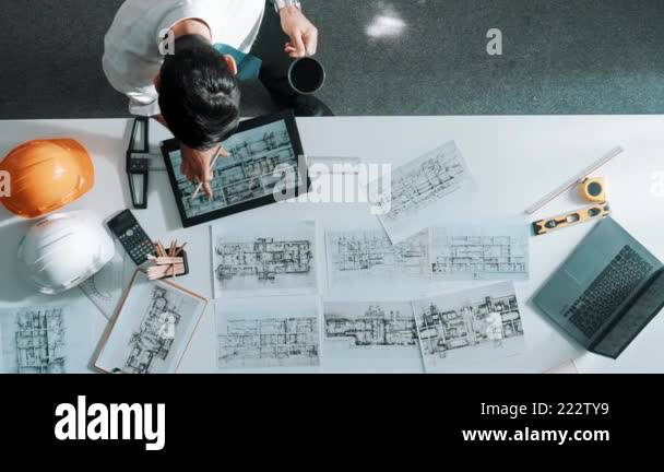 Top down view of engineer looking at tablet while using laptop to ...